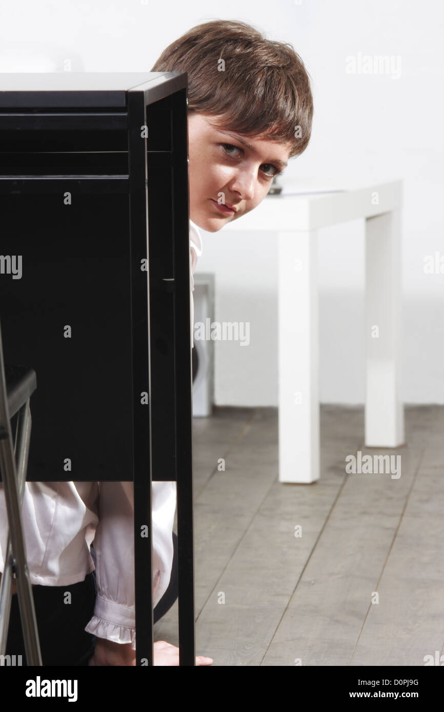 Businesswoman hiding behind desk Stock Photo - Alamy