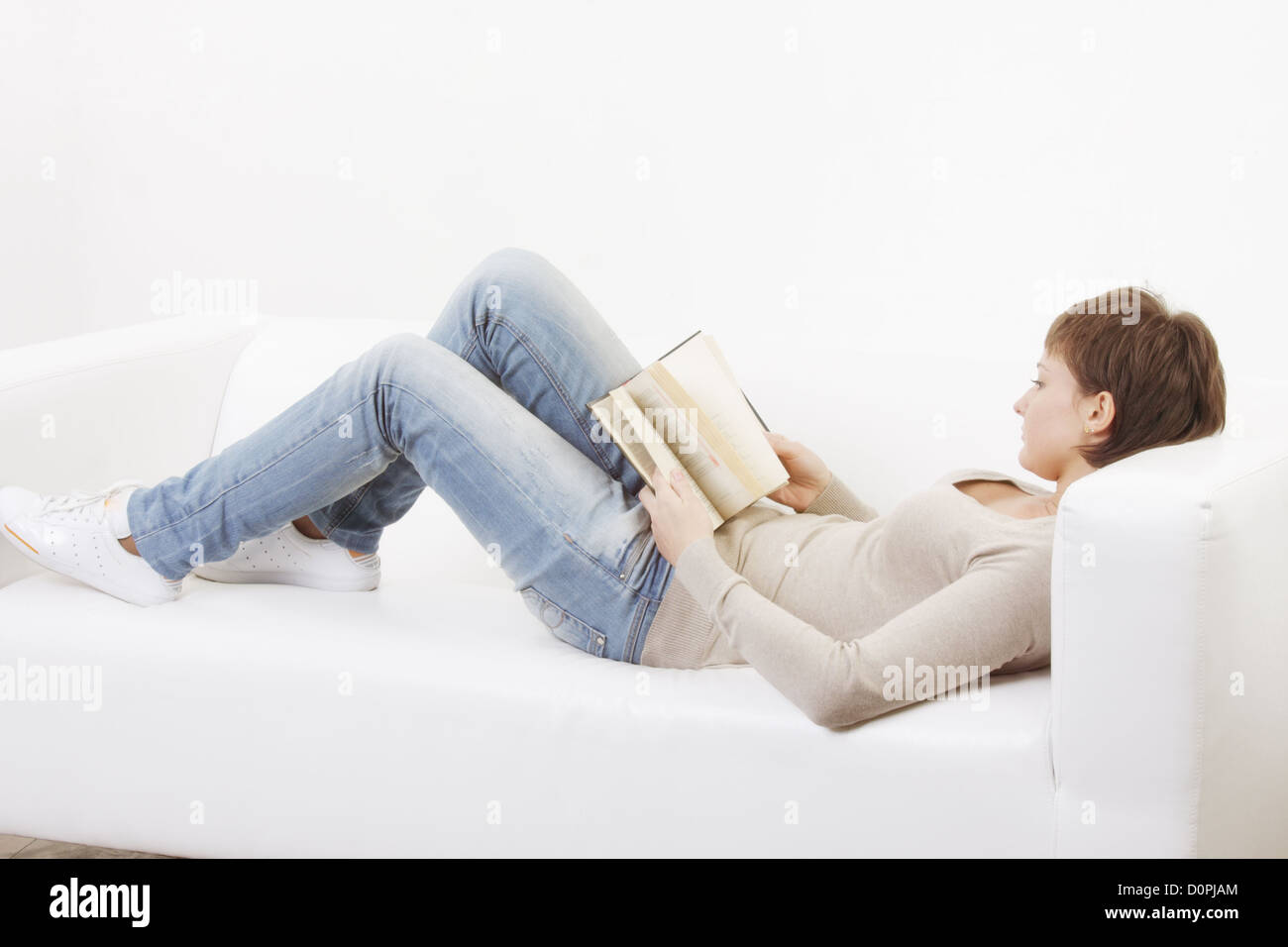 Young woman reading book laying on back Stock Photo - Alamy