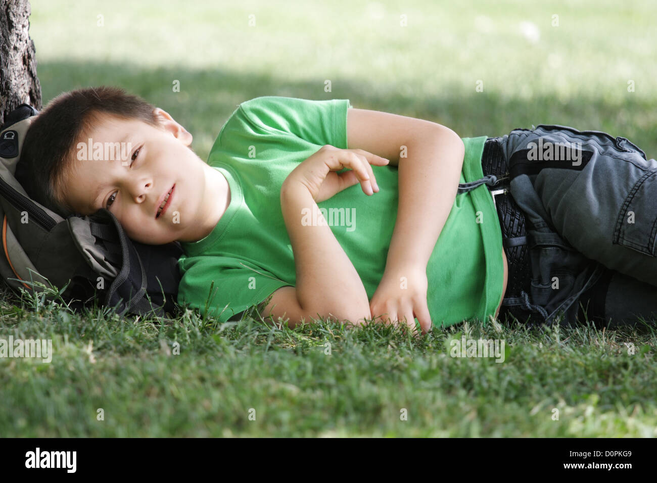 Boy laying down under tree Stock Photo - Alamy