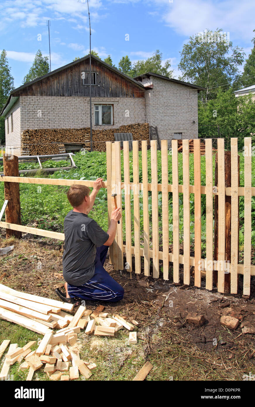 man builds fence Stock Photo - Alamy