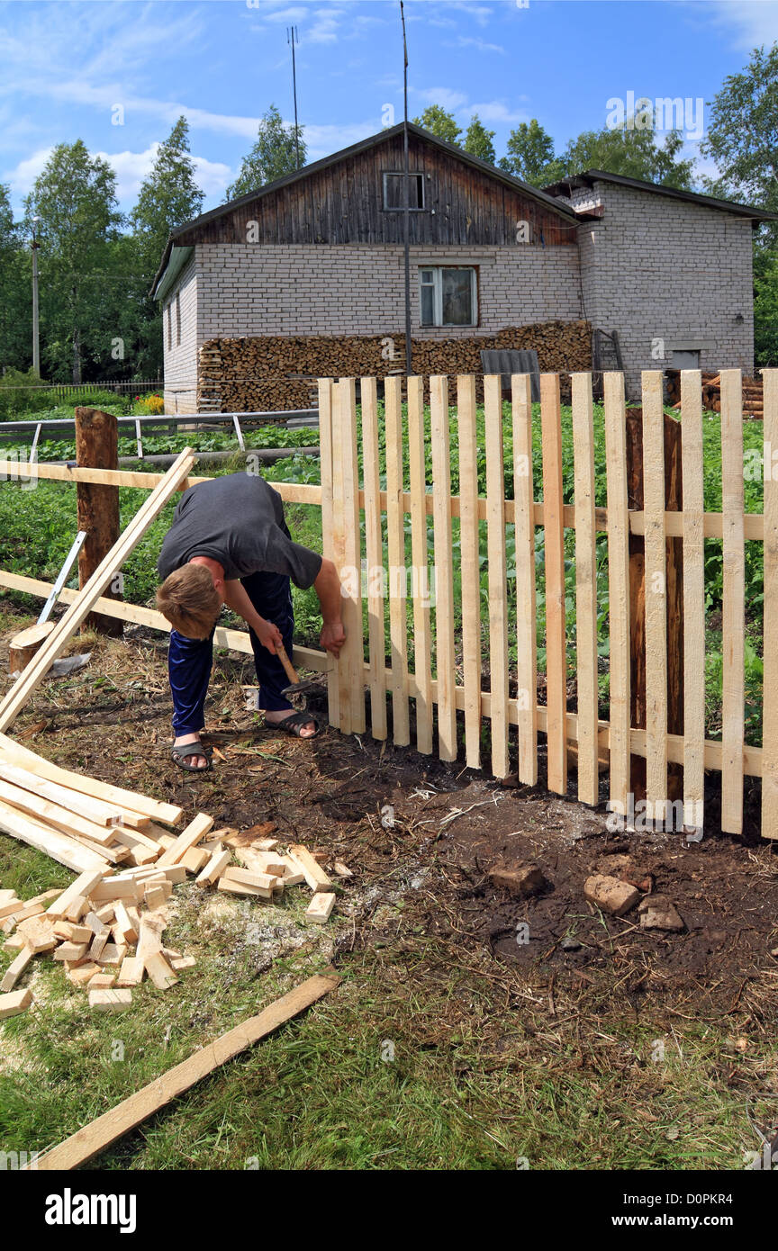 man builds fence Stock Photo - Alamy