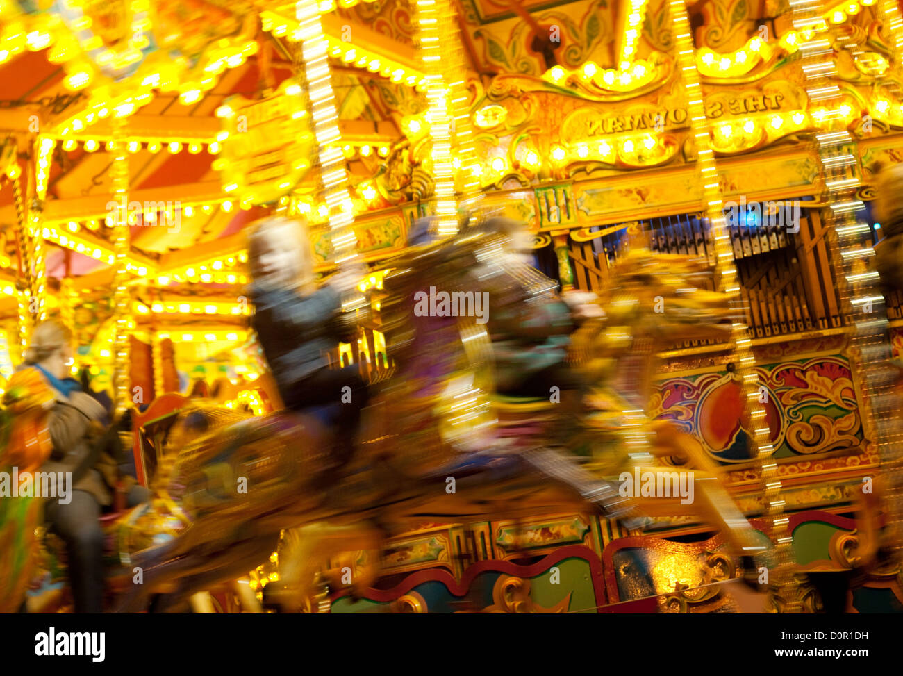 A girl child riding a horse on a carousel at a fair fairground, motion ...