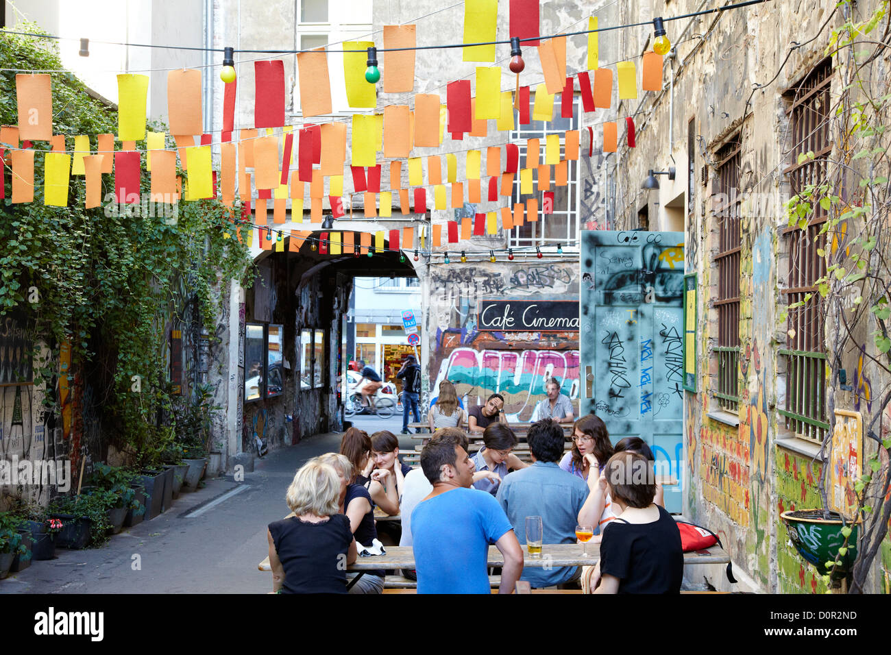 Typical graffiti court in Berlin, people talking in front of a café ...