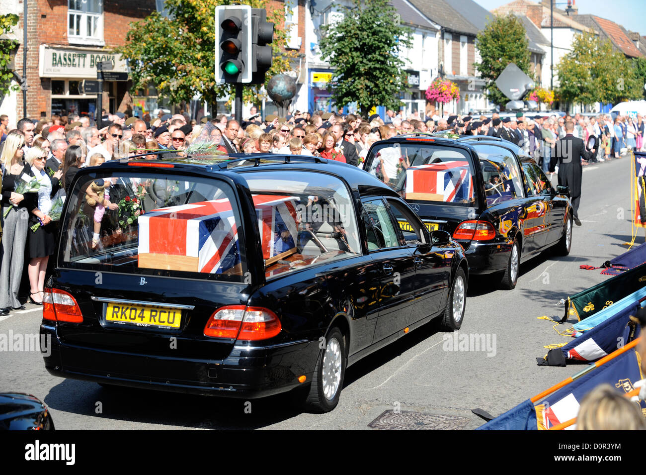 Friends and relatives throw flowers over a cortege of hearses during a ...