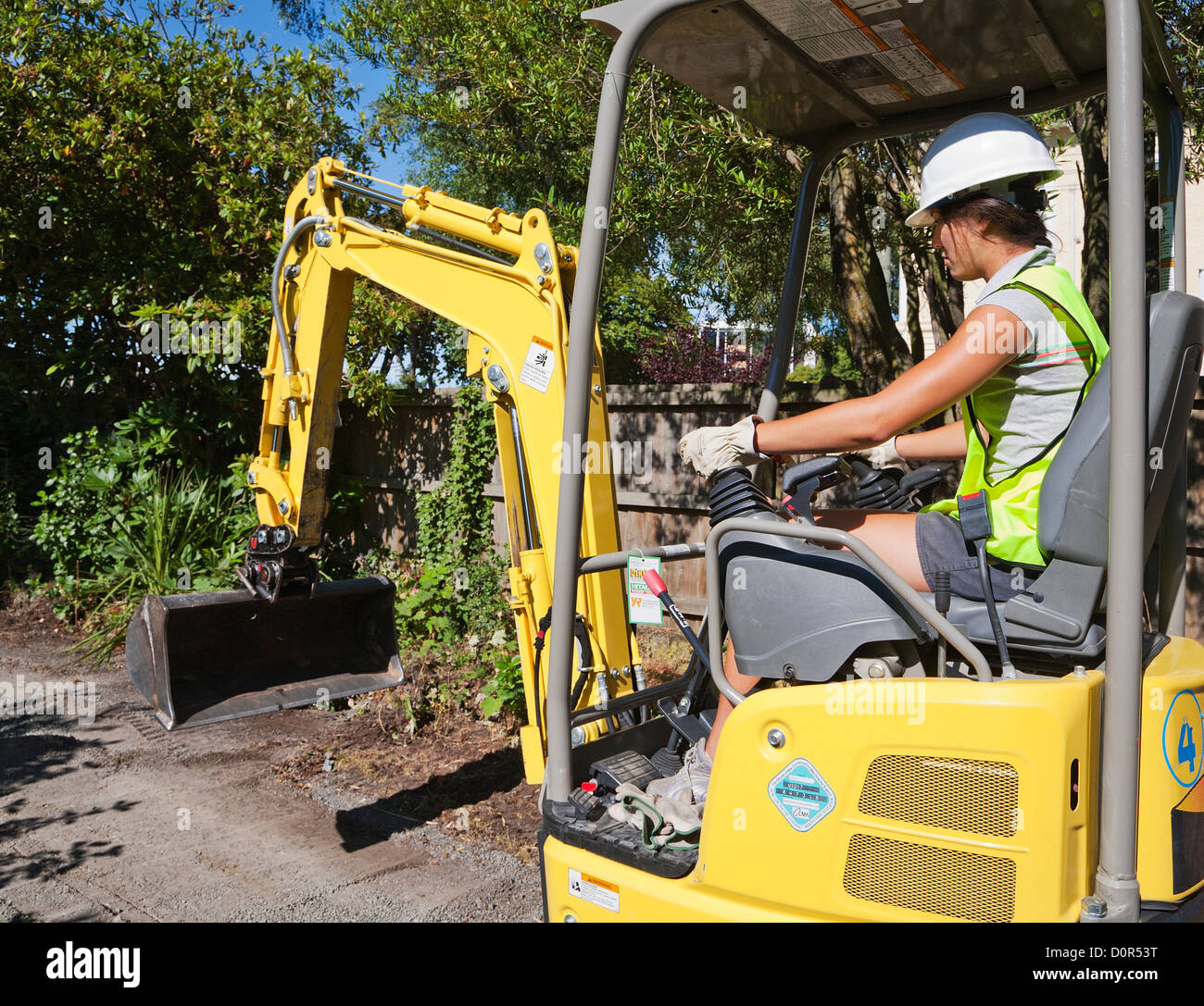 A young woman construction worker, working using a digger excavator ...