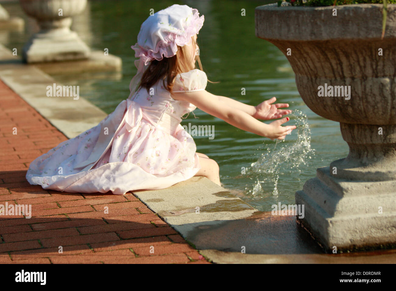 Little girl in dress splashing water at park Stock Photo - Alamy