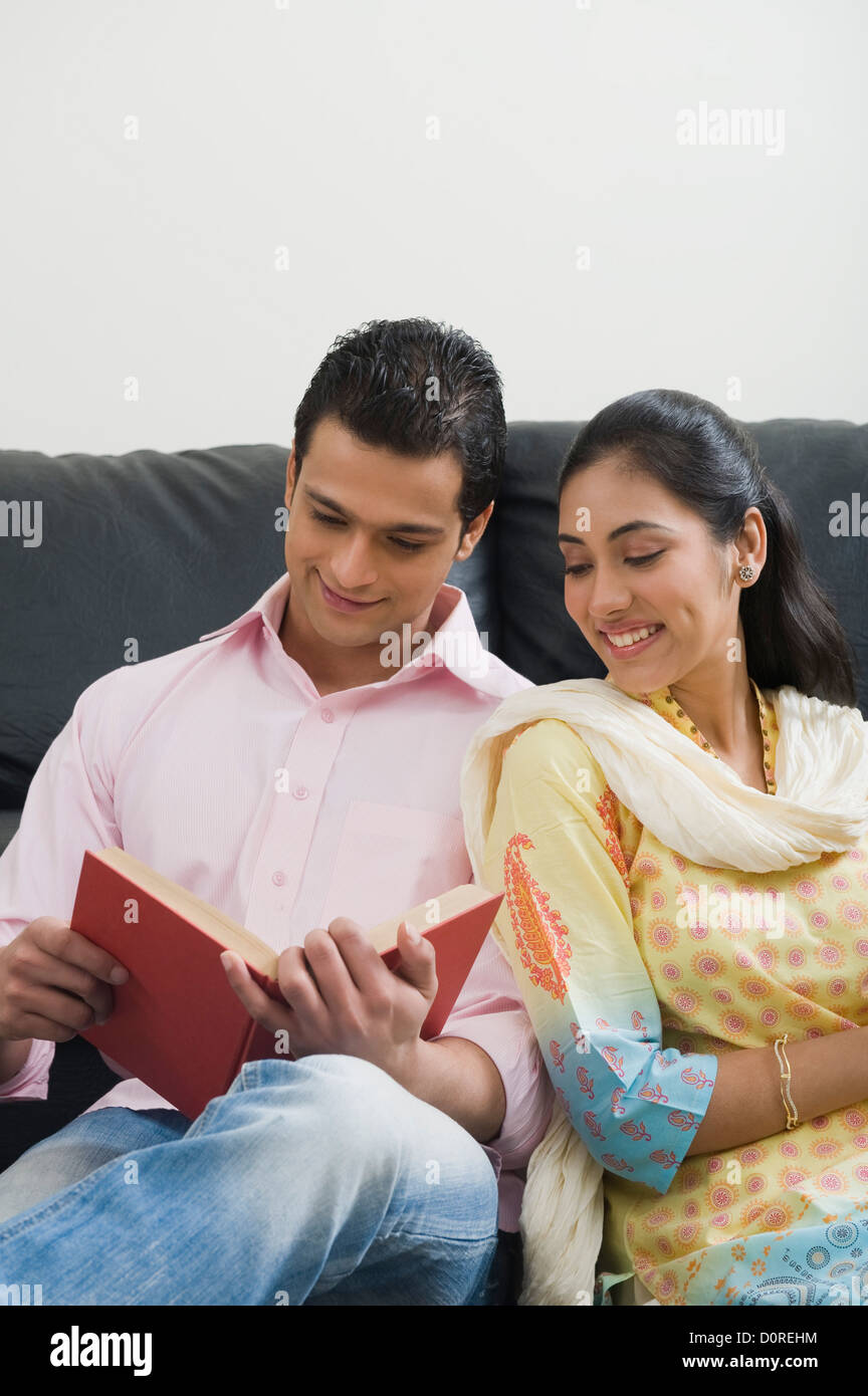 Couple reading a book and smiling Stock Photo - Alamy