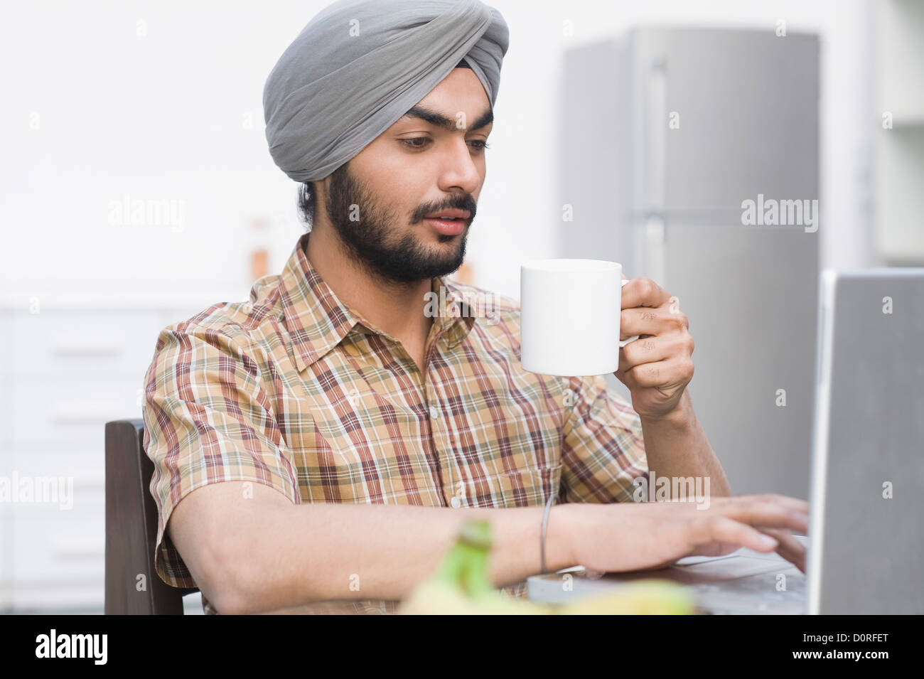 Man working on a laptop while drinking tea Stock Photo - Alamy