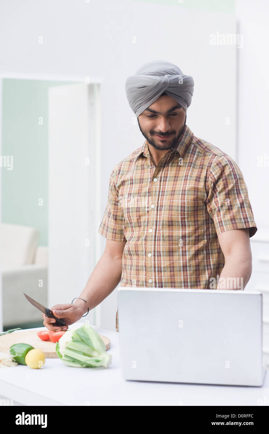 Man cooking with the recipe on a laptop Stock Photo - Alamy