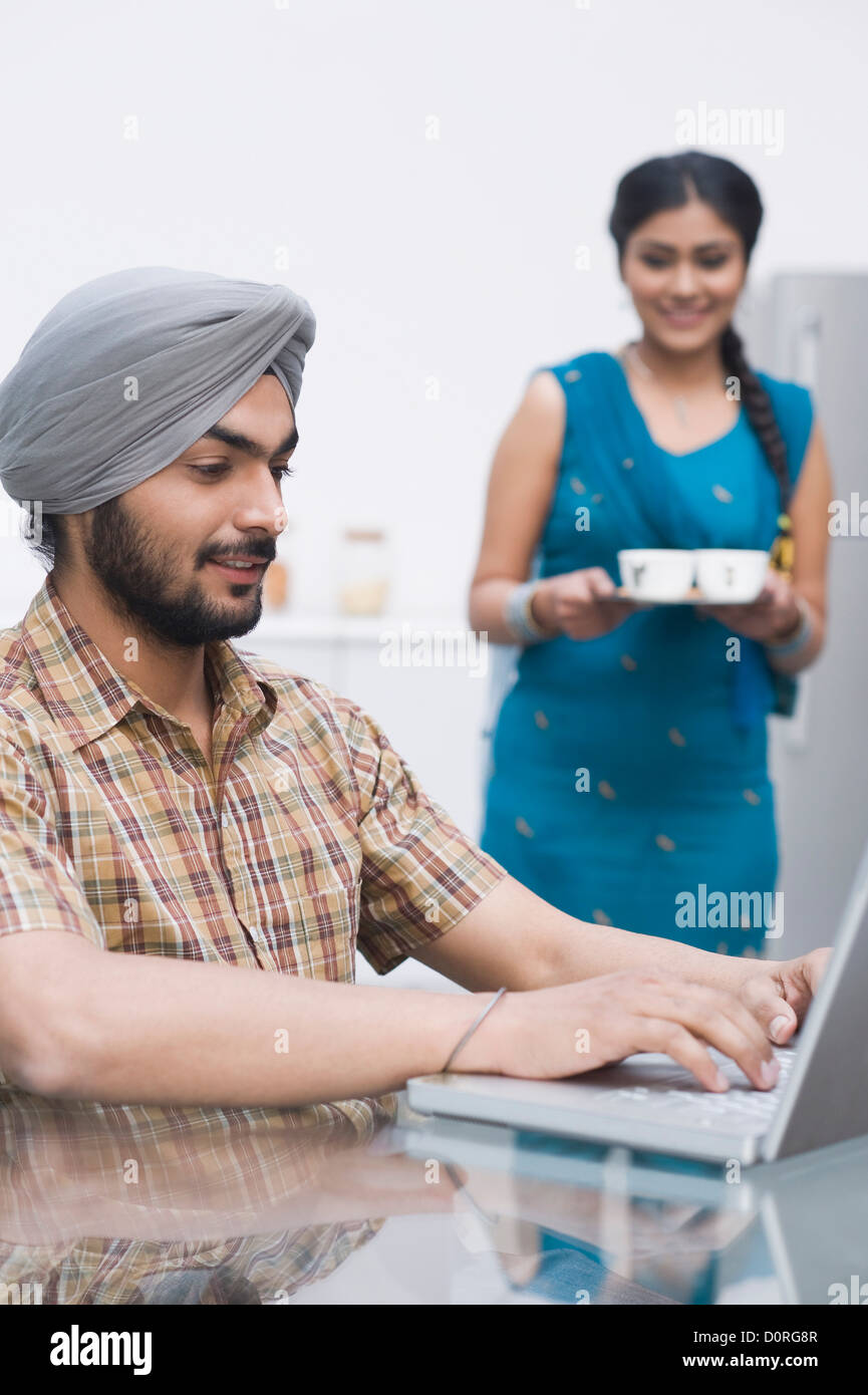 Woman bringing tea for her husband working on a laptop Stock Photo - Alamy
