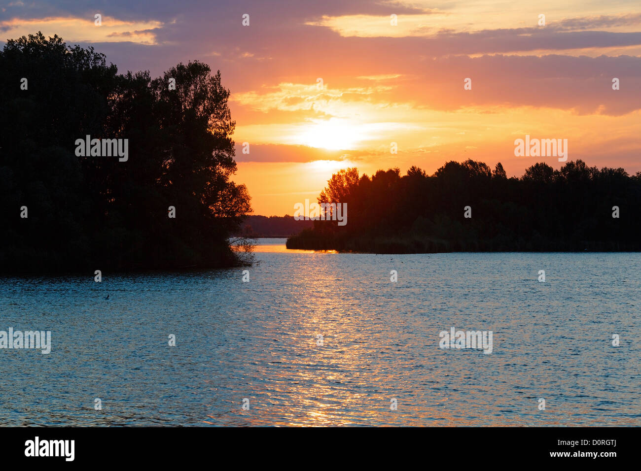 Pink-yellow sunset and sun reflection on lake water surface Stock Photo ...