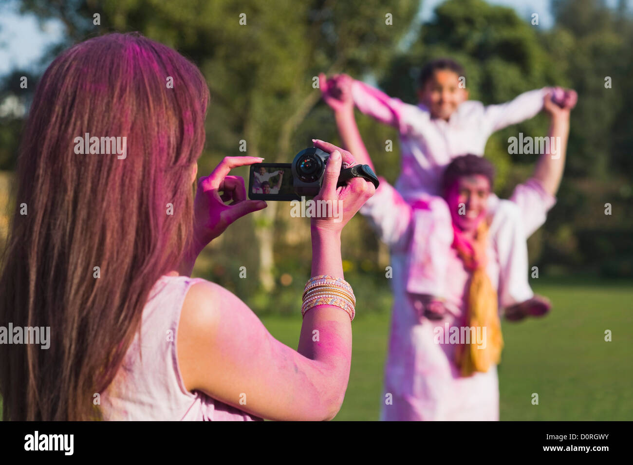 Woman filming her family with a video camera on Holi Stock Photo - Alamy