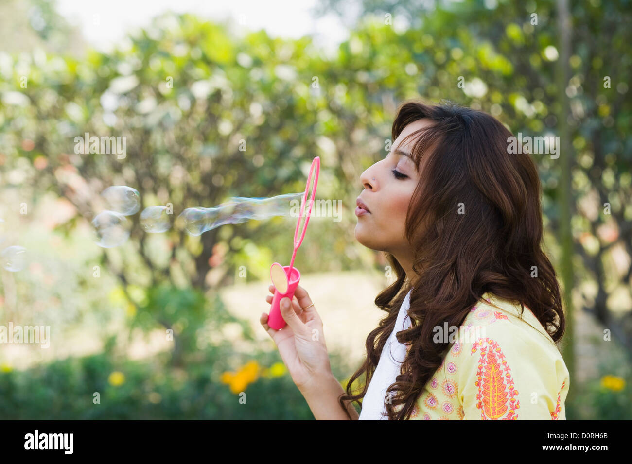 Woman blowing soap bubbles with a bubble wand Stock Photo - Alamy