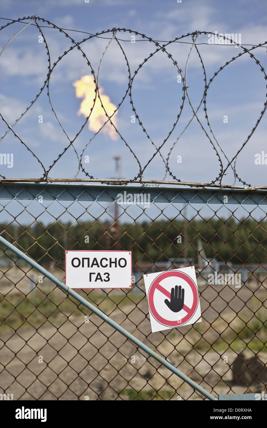 Gas flare behind fence Stock Photo - Alamy