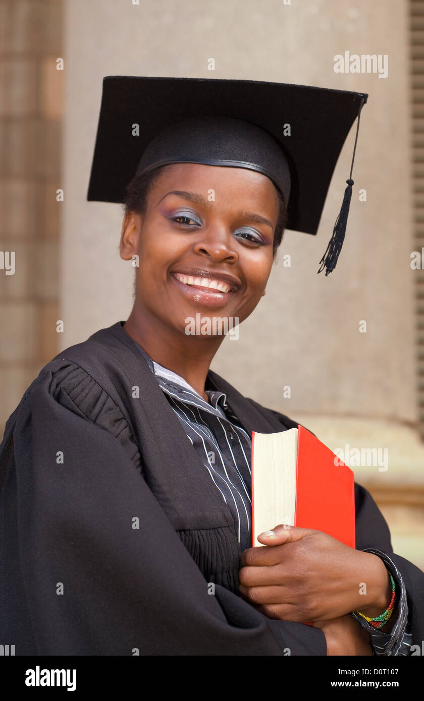 Graduating African American college student on campus with book and ...