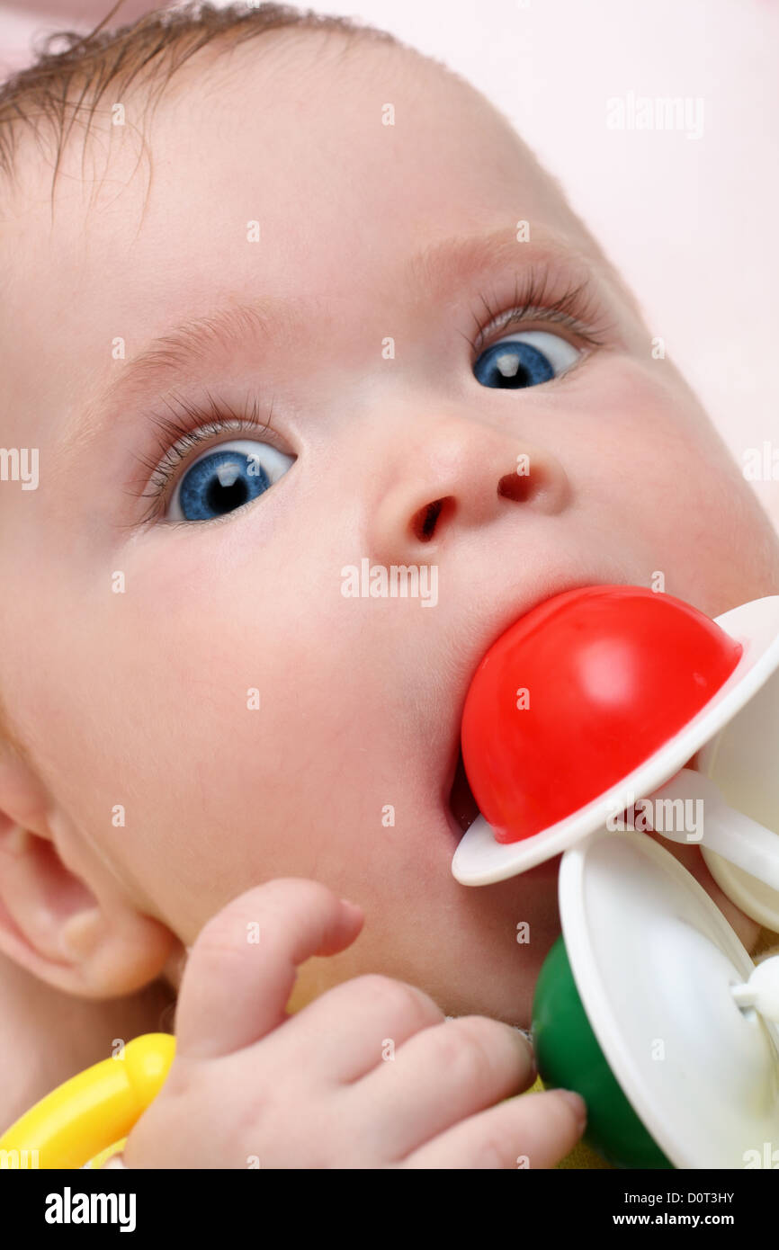 baby girl biting rattle Stock Photo - Alamy