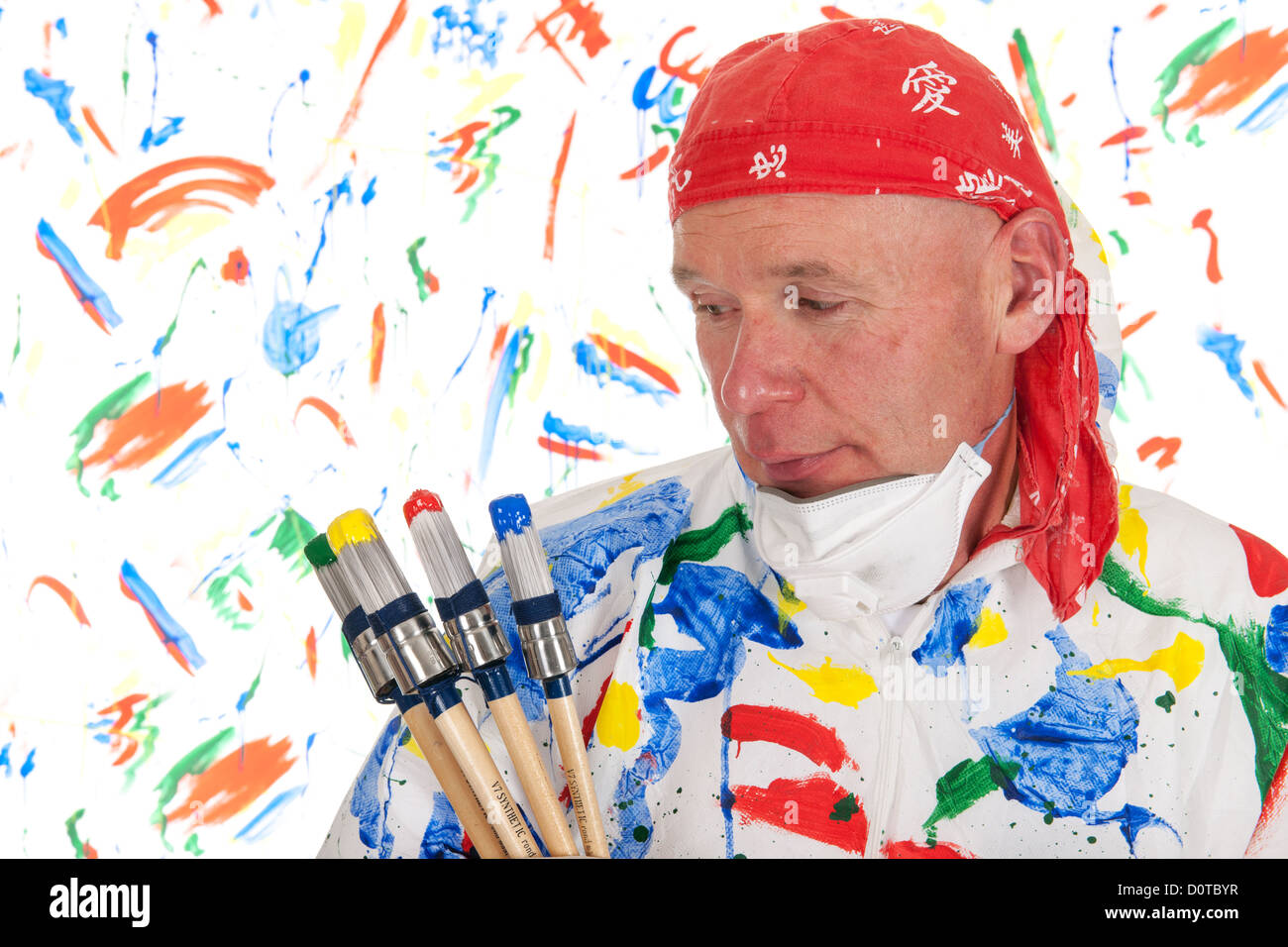 Painter with colorful paint brushes and safety mask is making a mess at ...