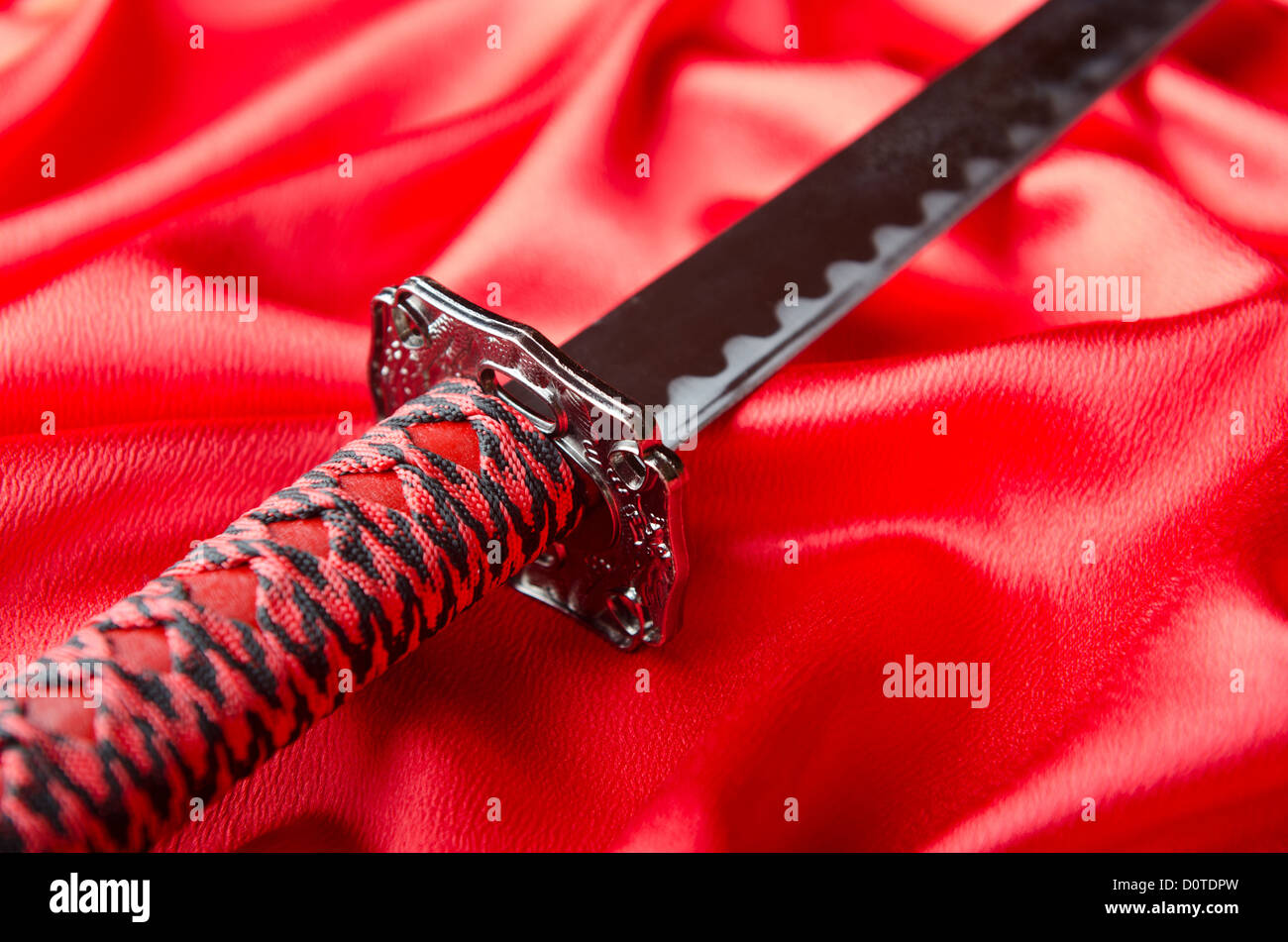 Japanese sword takana on red satin background Stock Photo - Alamy