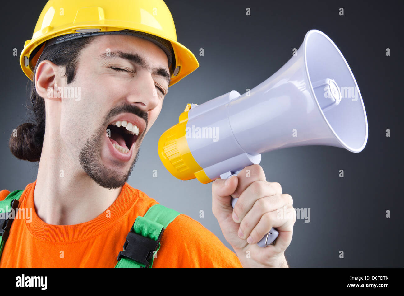 Construction worker with loudspeaker in studio Stock Photo - Alamy