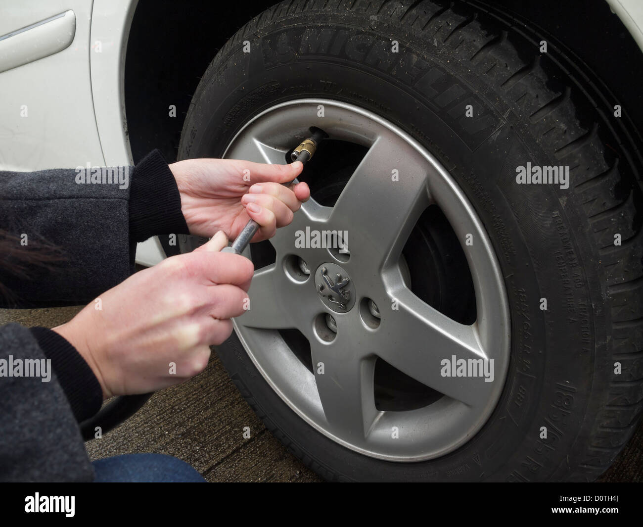 Young woman checking car tyre pressure Stock Photo - Alamy