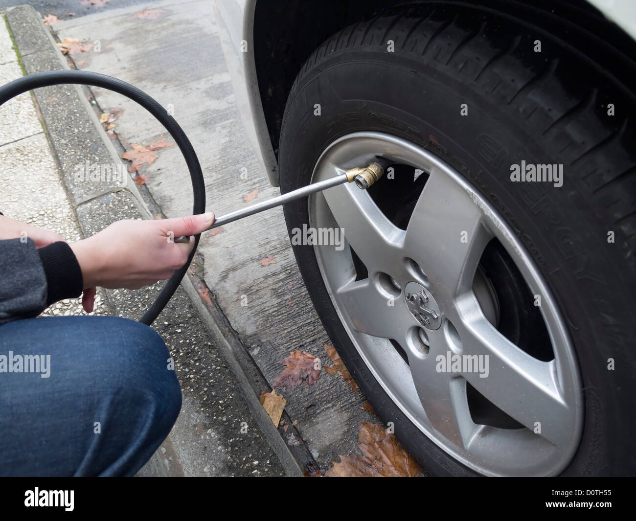 Young woman checking car tyre pressure Stock Photo - Alamy
