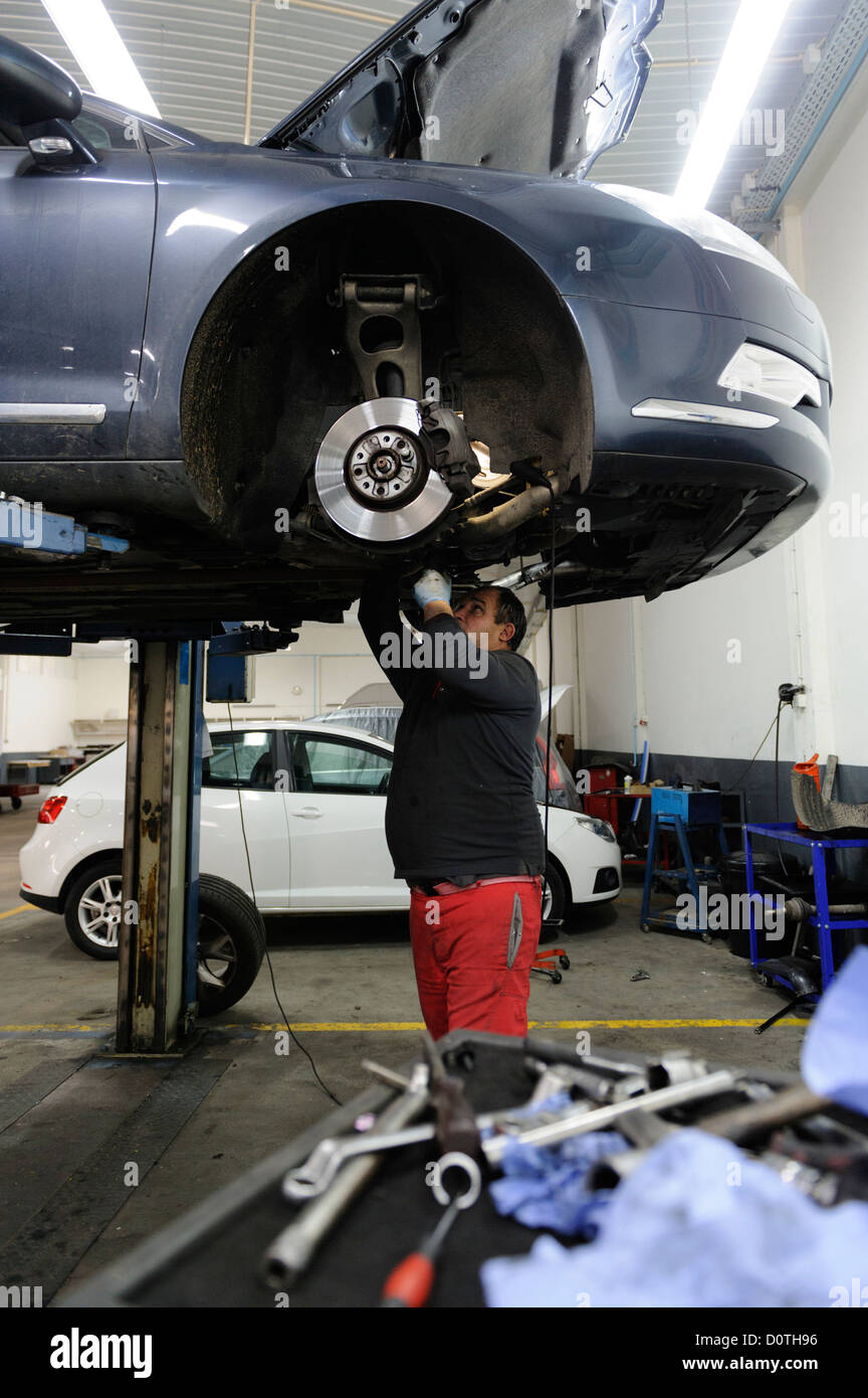Car mechanic checking a car raised on a hydraulic lift Stock Photo - Alamy