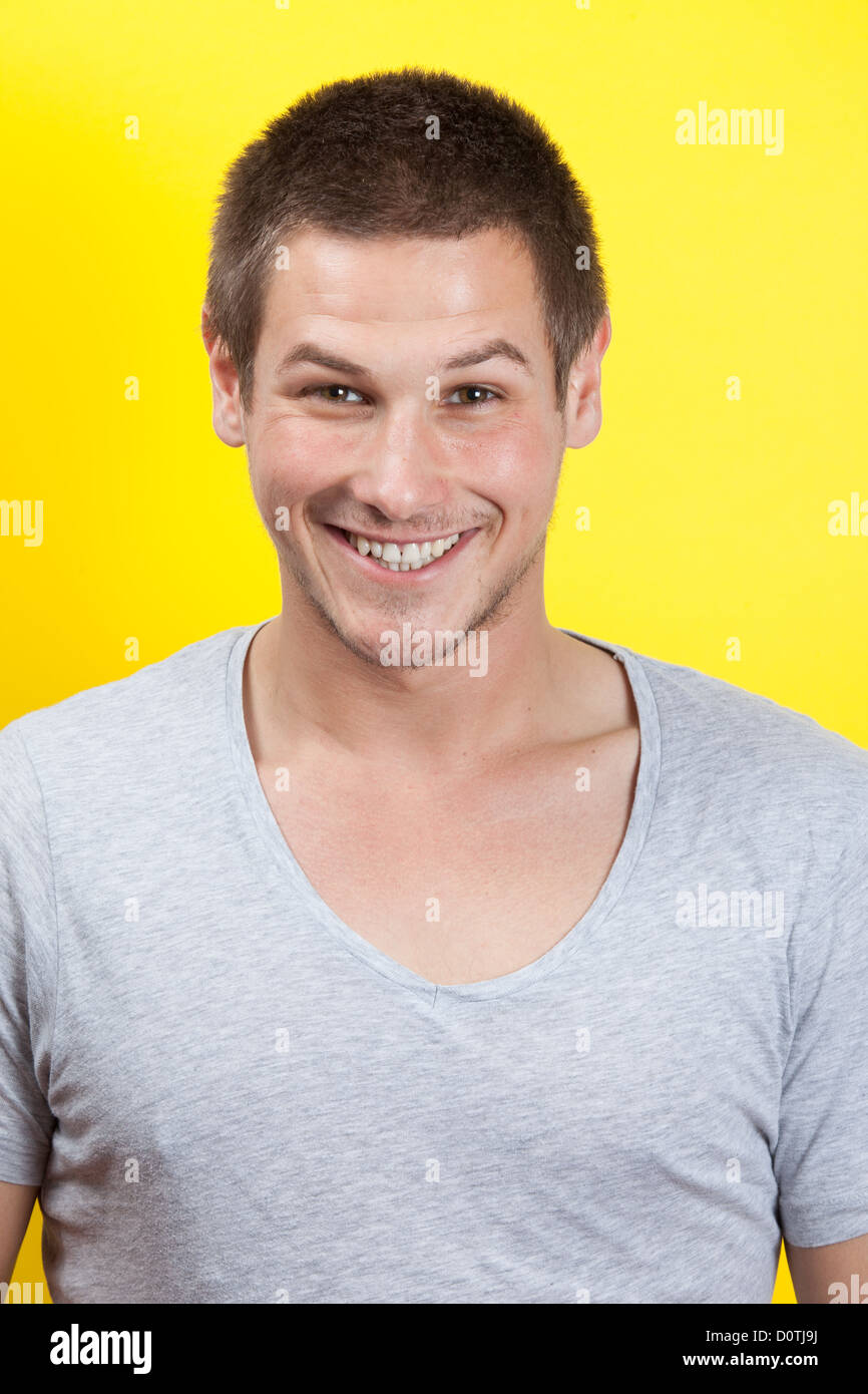 Handsome young man smiling in yellow background Stock Photo - Alamy