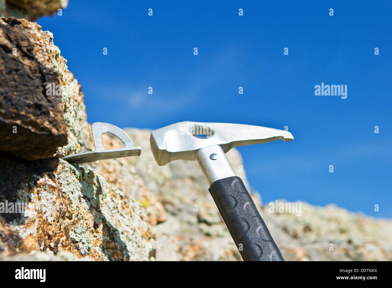 The climber hammers in hook for carbine into rock Stock Photo - Alamy