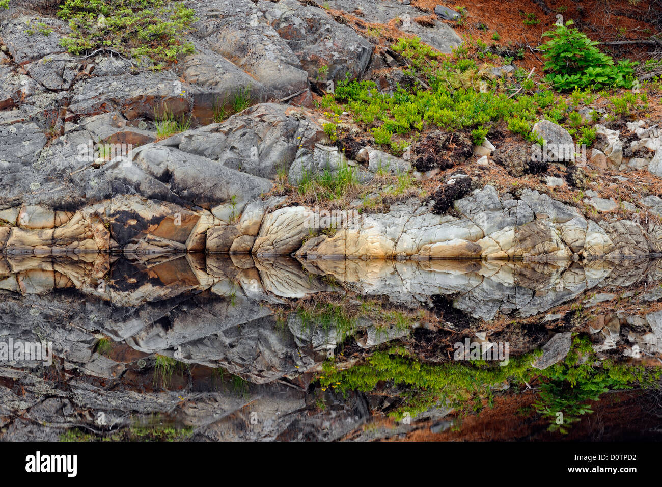 Rock outcrops reflected in an inlet of the McGregor Bay, near Whitefish ...