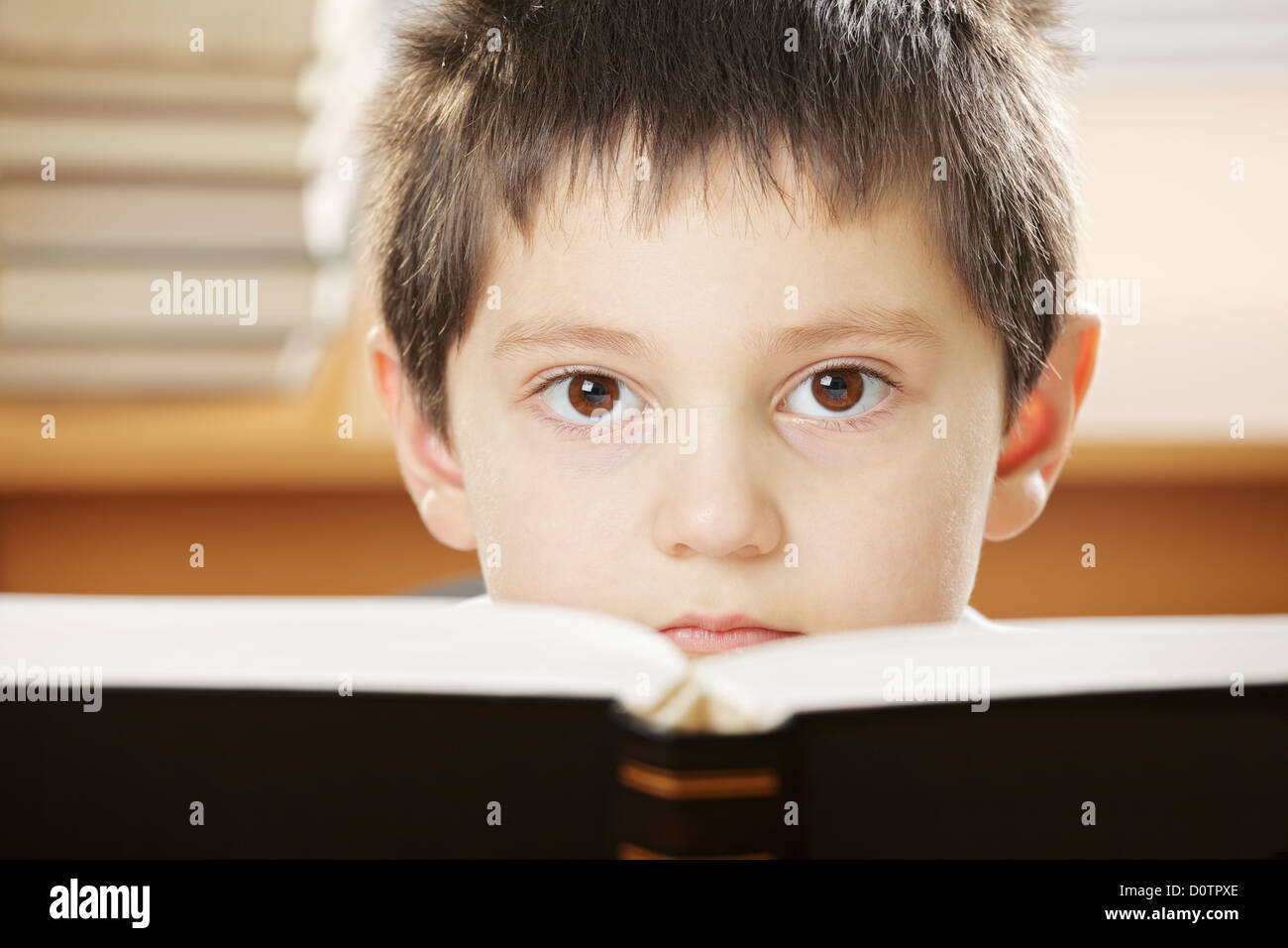 Boy looking over book Stock Photo - Alamy