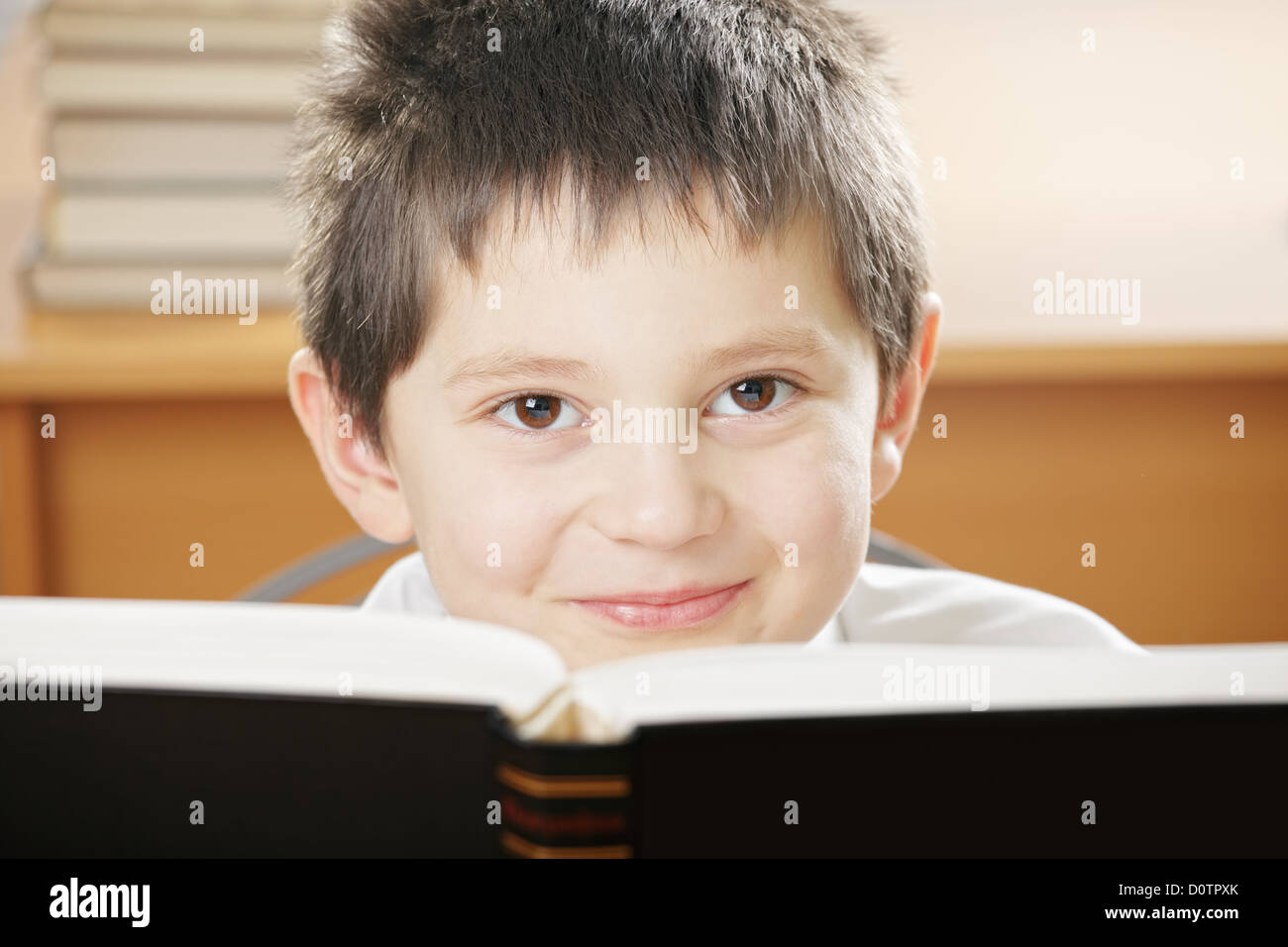 Smiling boy looking over book Stock Photo - Alamy