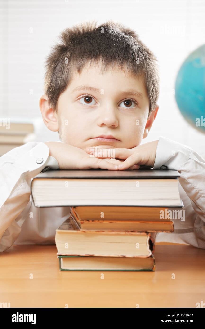 Boring boy leaning on stack of books Stock Photo - Alamy