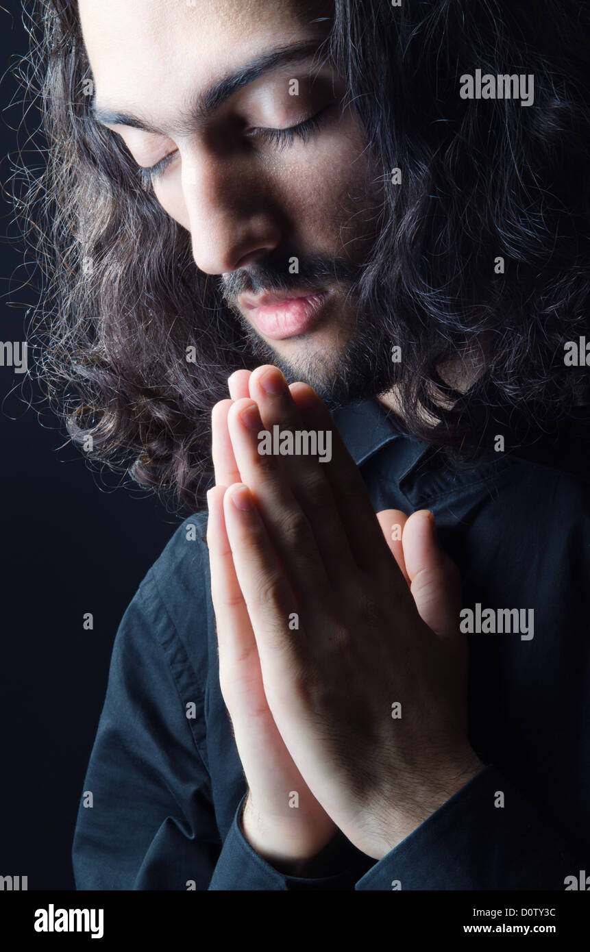 Young man praying in darkness Stock Photo - Alamy