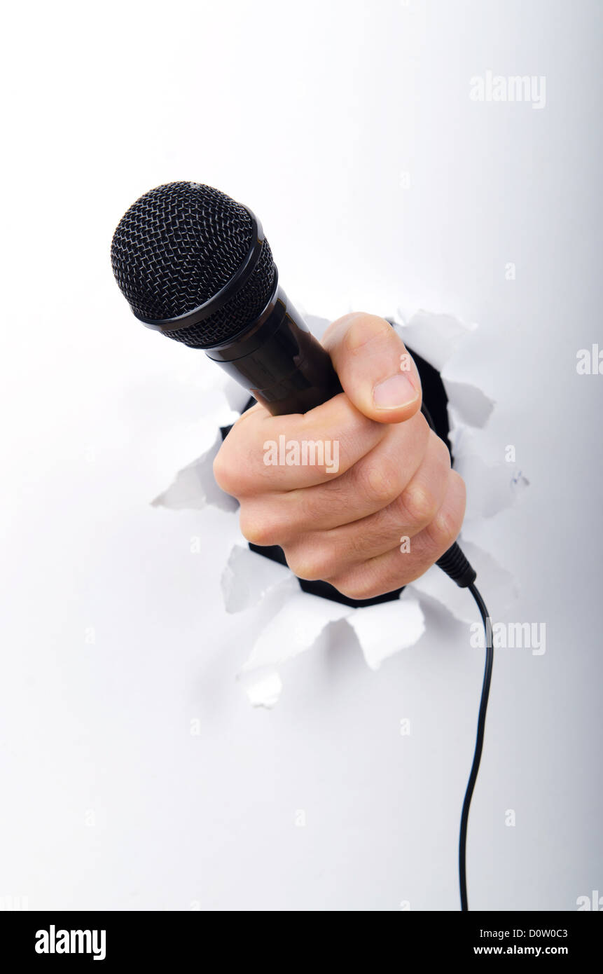 Hand holding microphone through hole in paper Stock Photo - Alamy