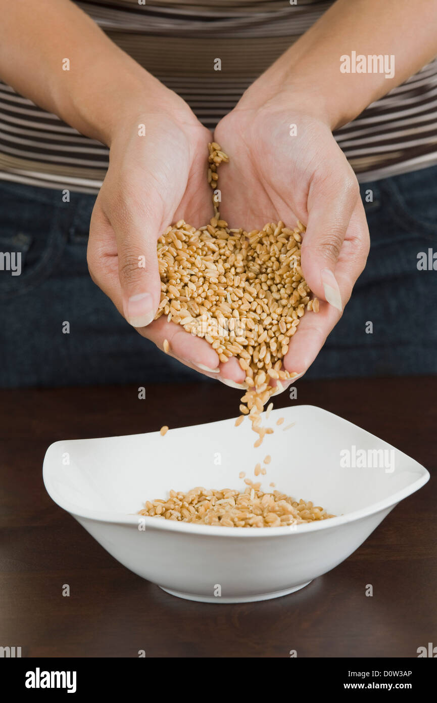 Mid section view of a woman pouring wheat in a bowl Stock Photo - Alamy