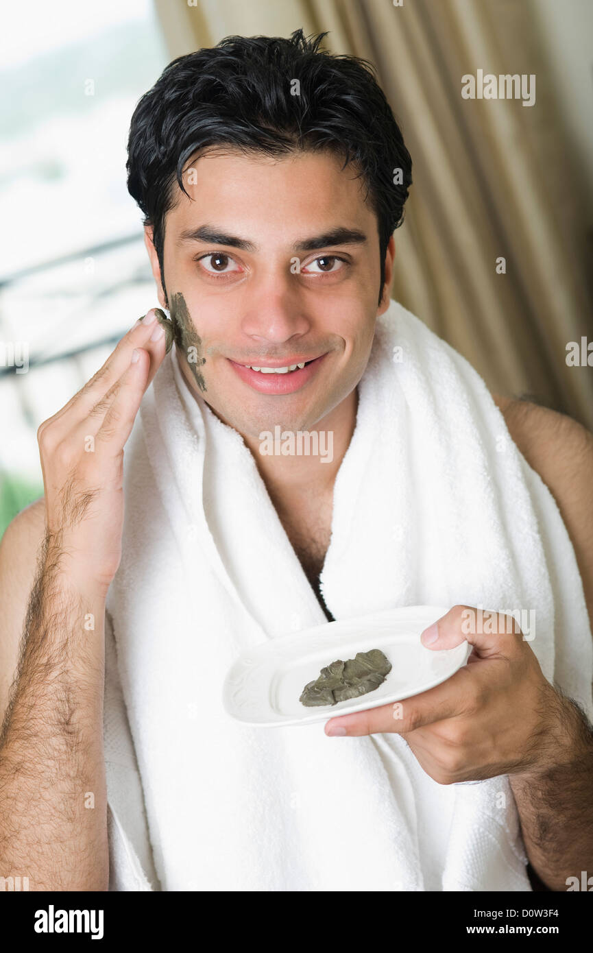 Portrait of a man applying mud pack on his face Stock Photo - Alamy