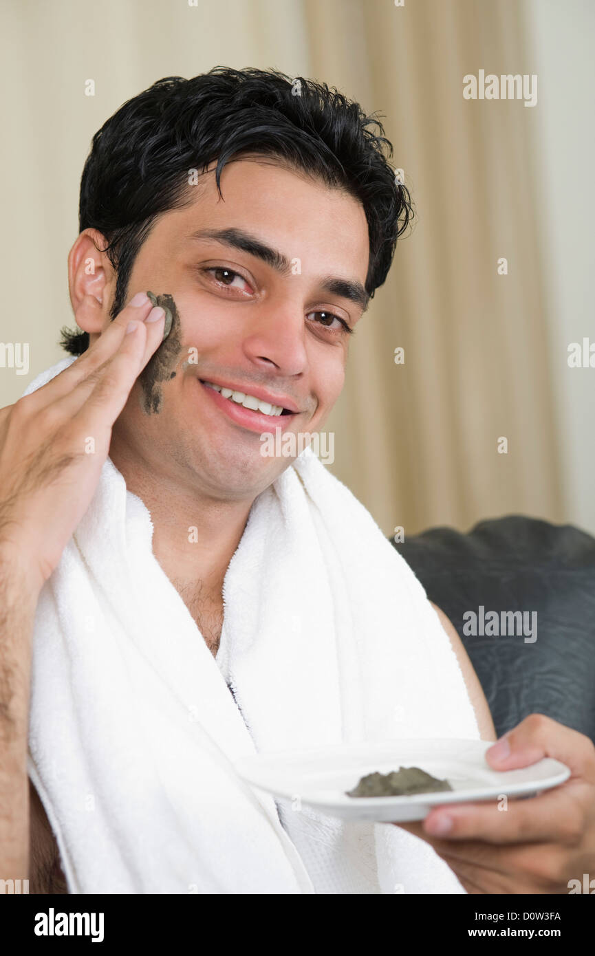 Portrait of a man applying mud pack on his face Stock Photo - Alamy