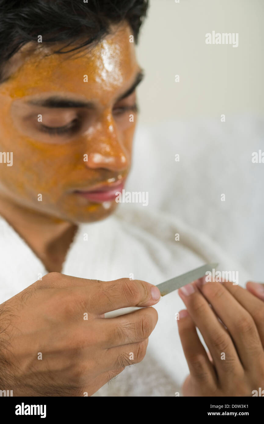 Close-up of a man with peel off mask filing his nails Stock Photo - Alamy