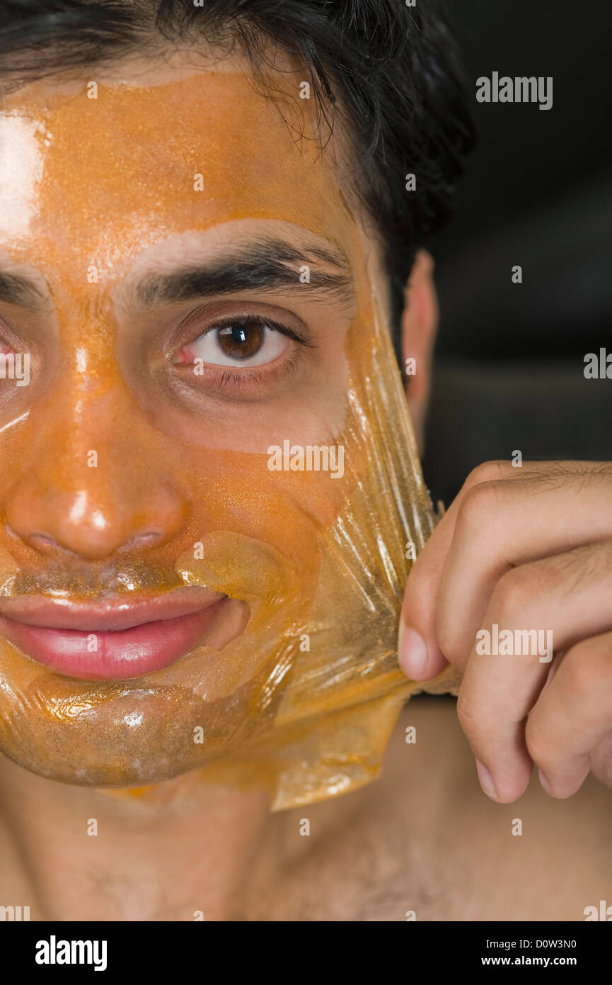 Portrait of a man peeling off facial mask from face Stock Photo - Alamy