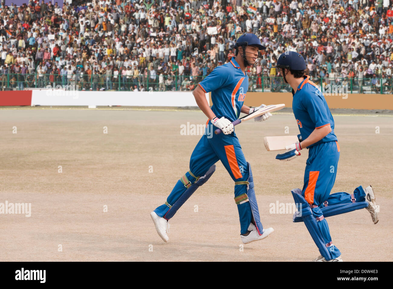 Two cricket batsmen passing each other while running between the ...