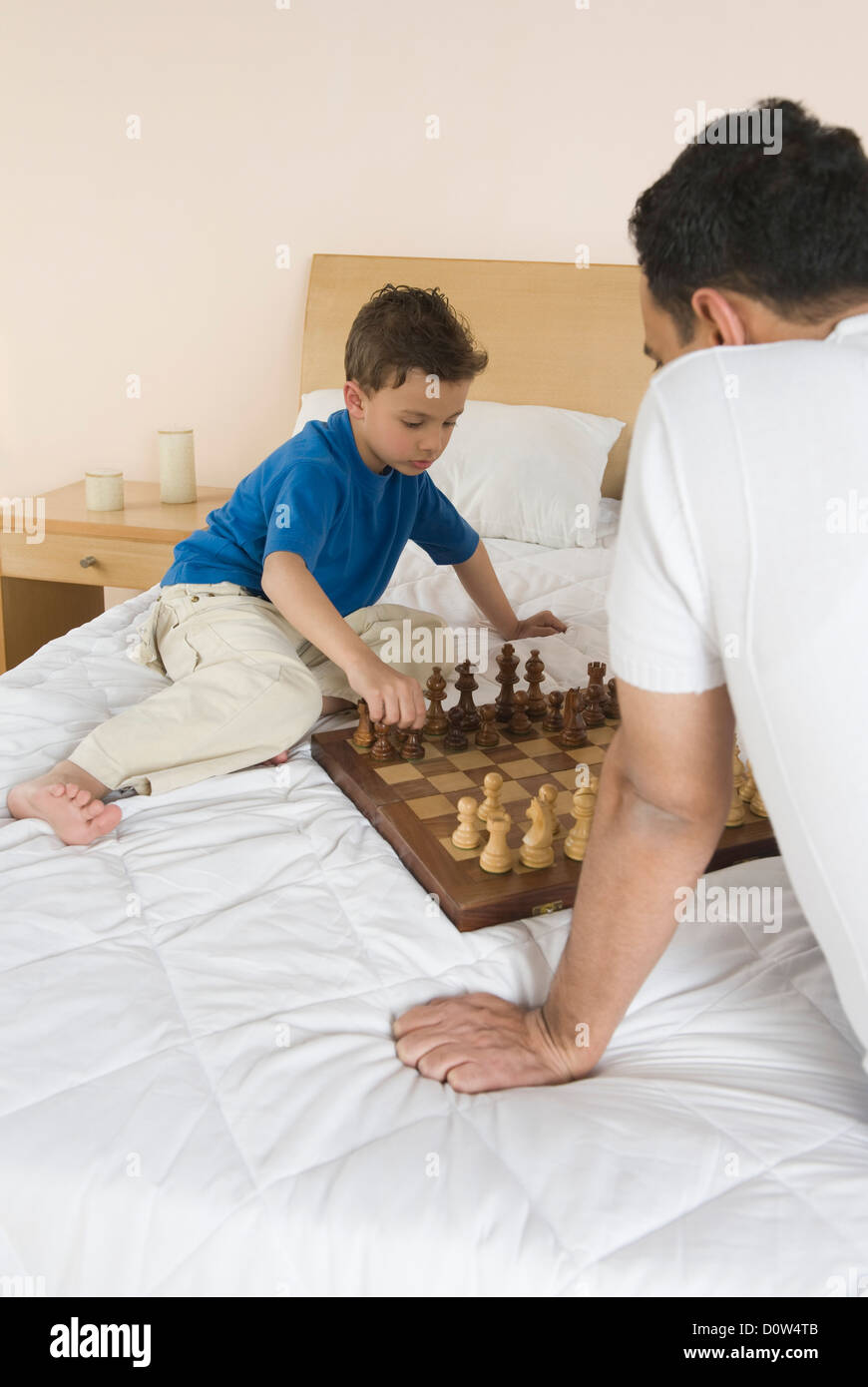 Man and his son playing chess on the bed Stock Photo - Alamy