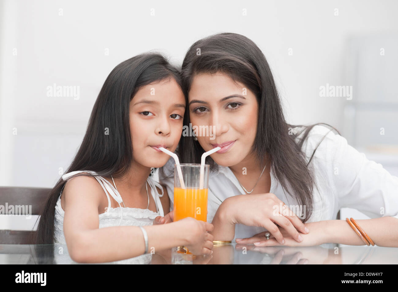 Woman and her daughter sharing a glass of juice Stock Photo - Alamy