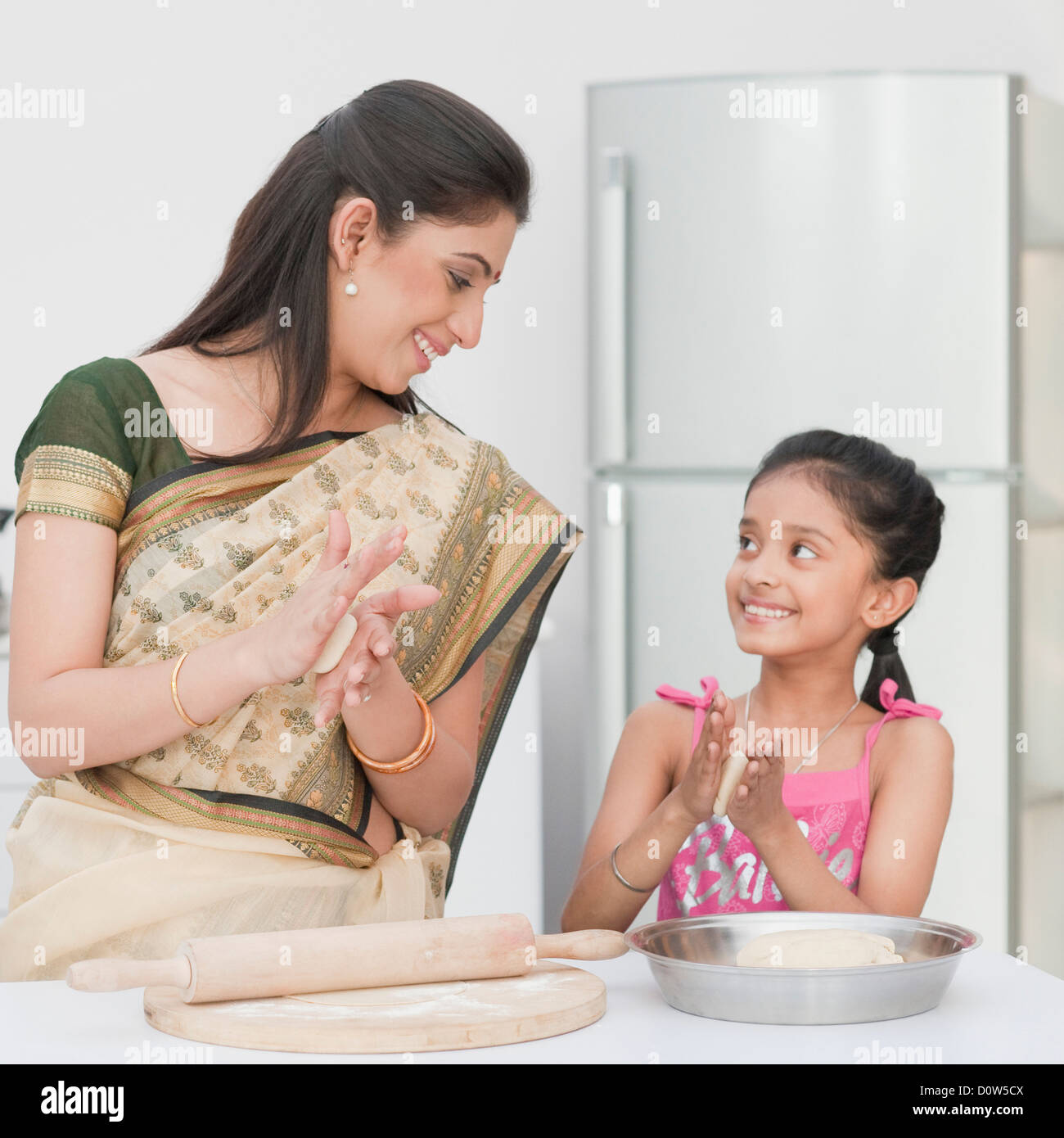 Girl learning cooking with the help of her mother Stock Photo - Alamy