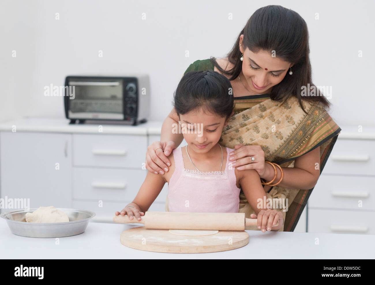 Girl learning cooking with the help of her mother Stock Photo - Alamy