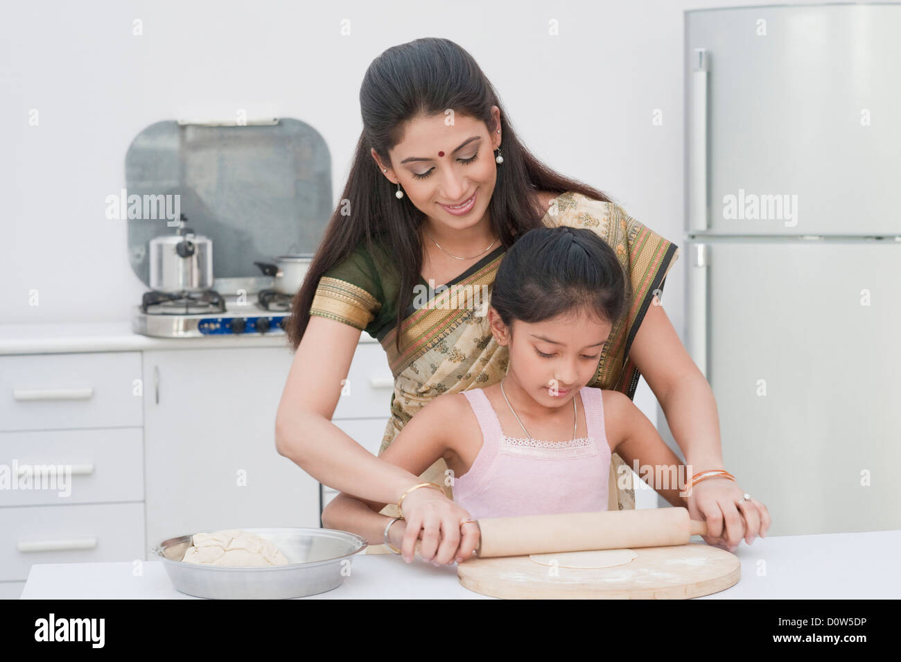 Girl learning cooking with the help of her mother Stock Photo - Alamy