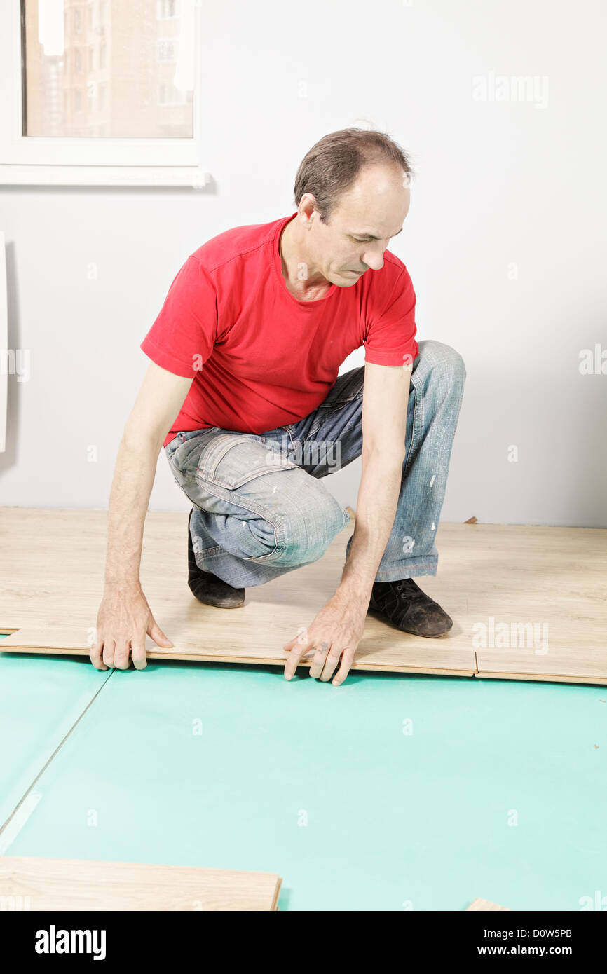 Guy in red installing flooring Stock Photo - Alamy
