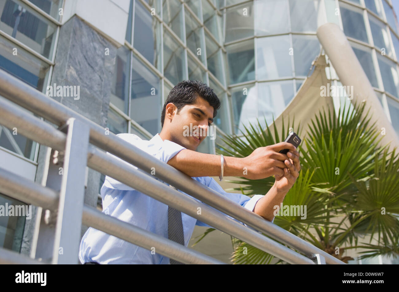 Low angle view of a businessman text messaging on a mobile phone ...