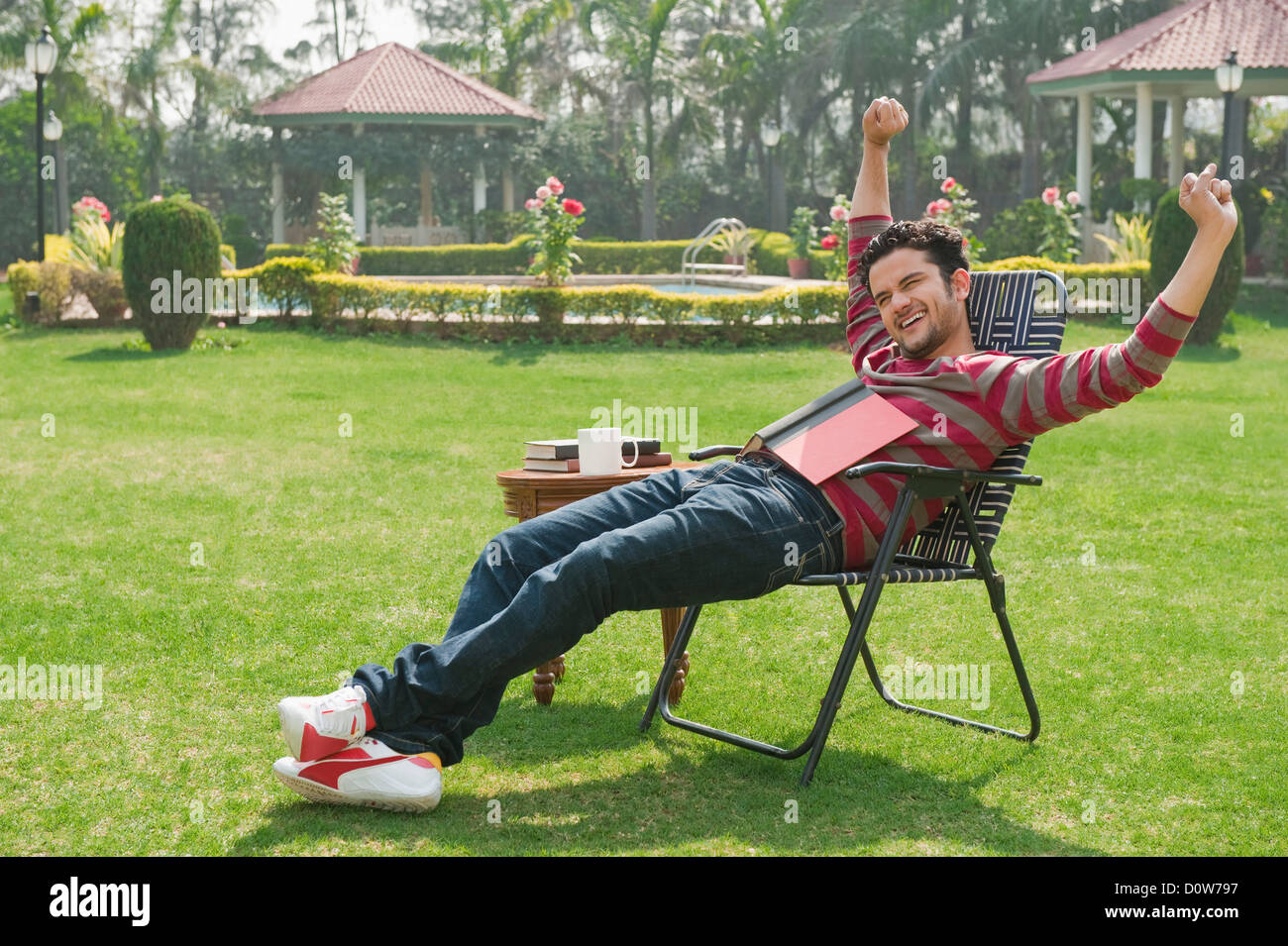 Man stretching his arms while reading a book Stock Photo - Alamy