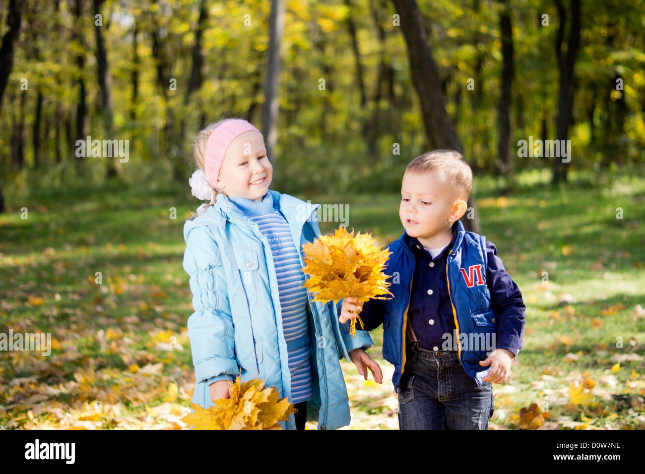 Happy kids playing in autumn woodland carrying large handfuls of ...