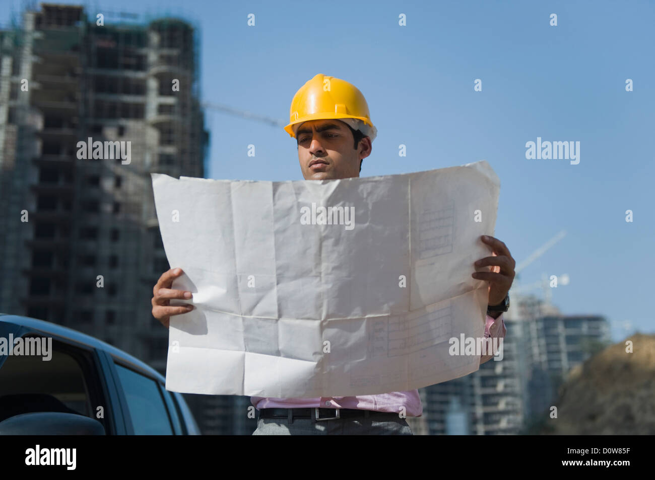 Architect looking at a blueprint at a construction site, Gurgaon ...
